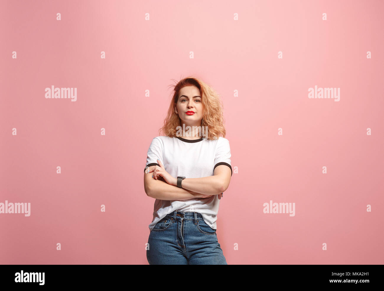 The serious business woman standing and looking at camera against pink ...