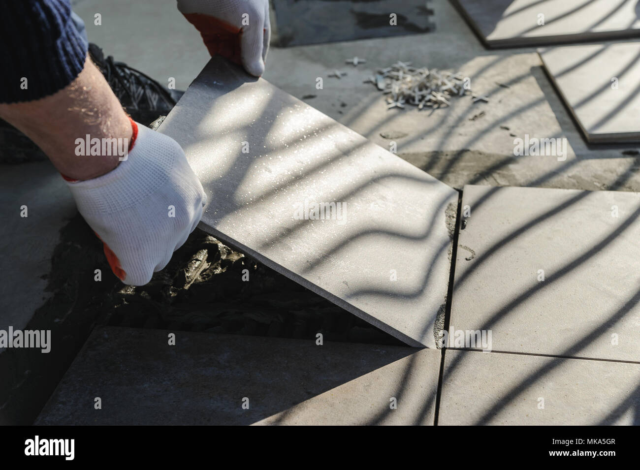 Laying Ceramic Tiles. Worker putting tiles on the balcony Stock Photo ...