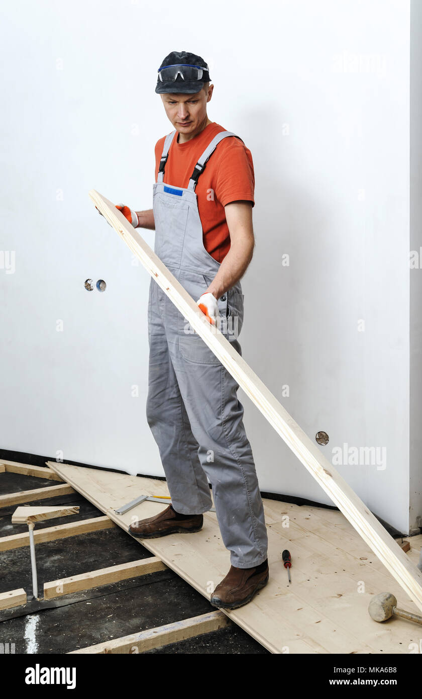 Installation of the wooden floor. Worker holds the wooden floorboards ...