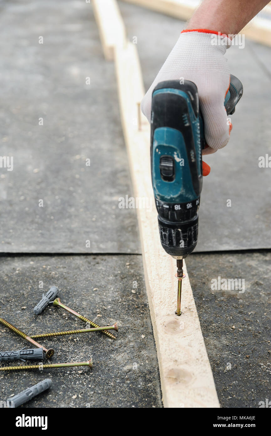 Worker twists the screw fixing wooden beams Stock Photo - Alamy