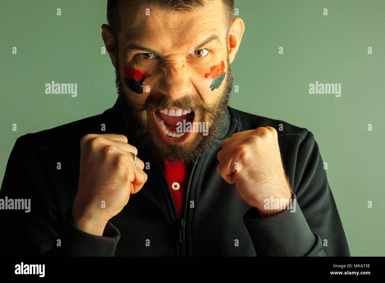 Portrait of a man with the flag of the Germany painted on him face ...