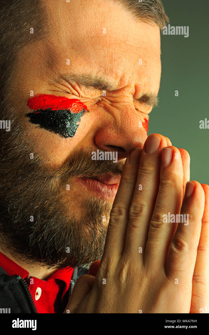 Portrait of a man with the flag of the Germany painted on him face ...