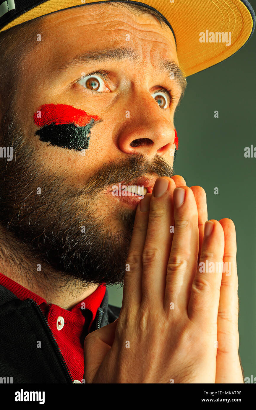Portrait of a man with the flag of the Germany painted on him face ...