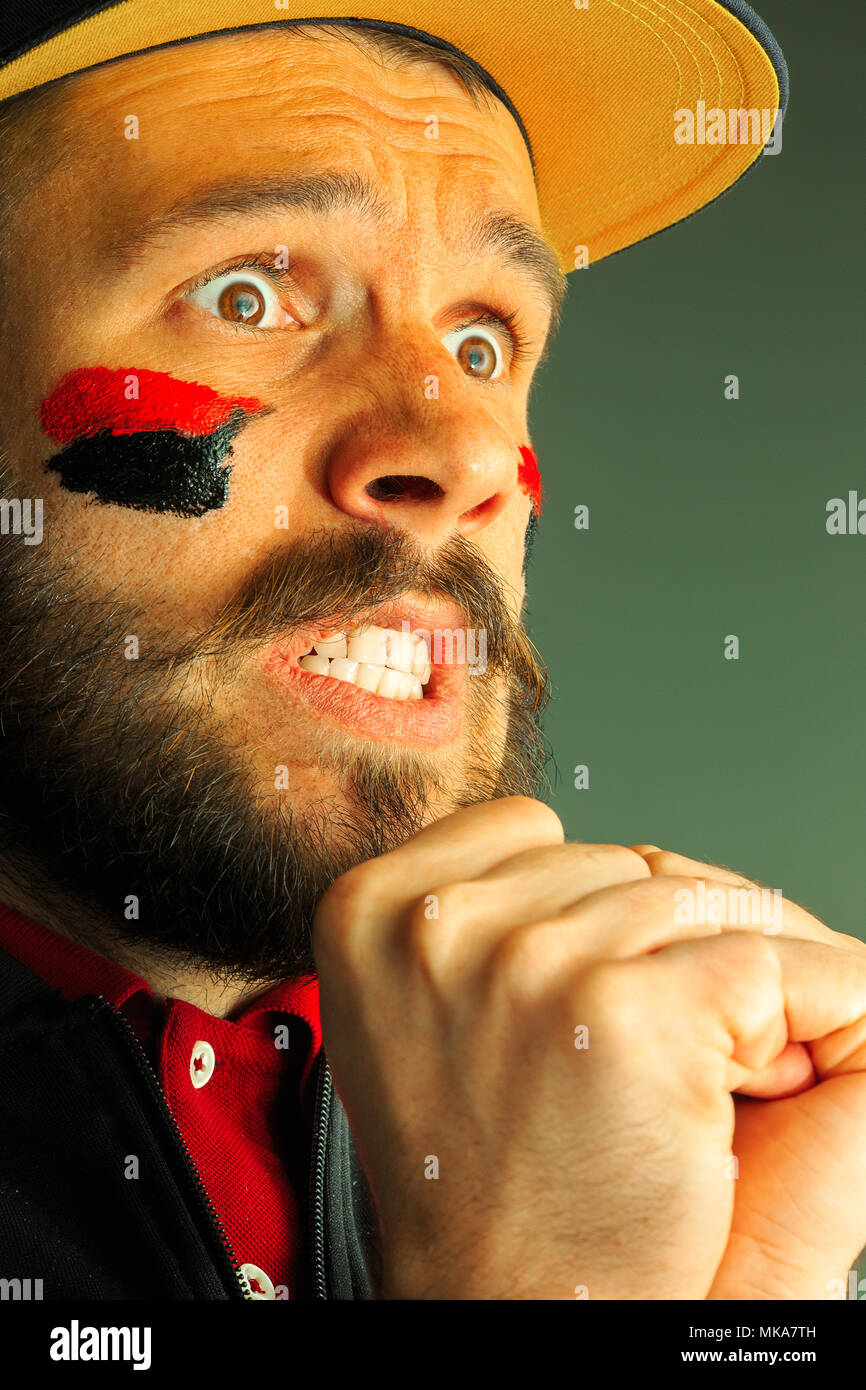 Portrait of a man with the flag of the Germany painted on him face ...