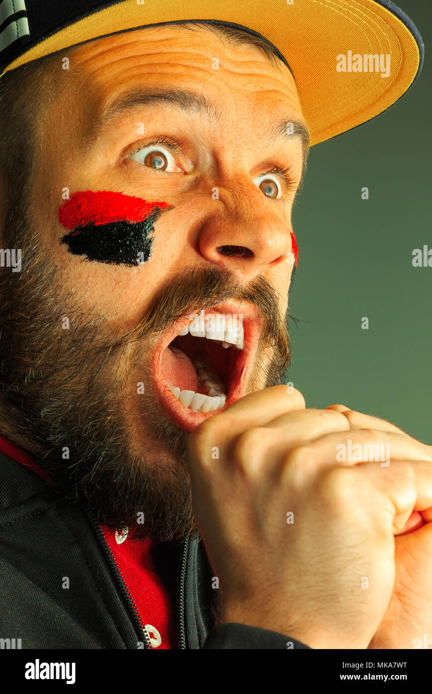 Portrait of a man with the flag of the Germany painted on him face ...