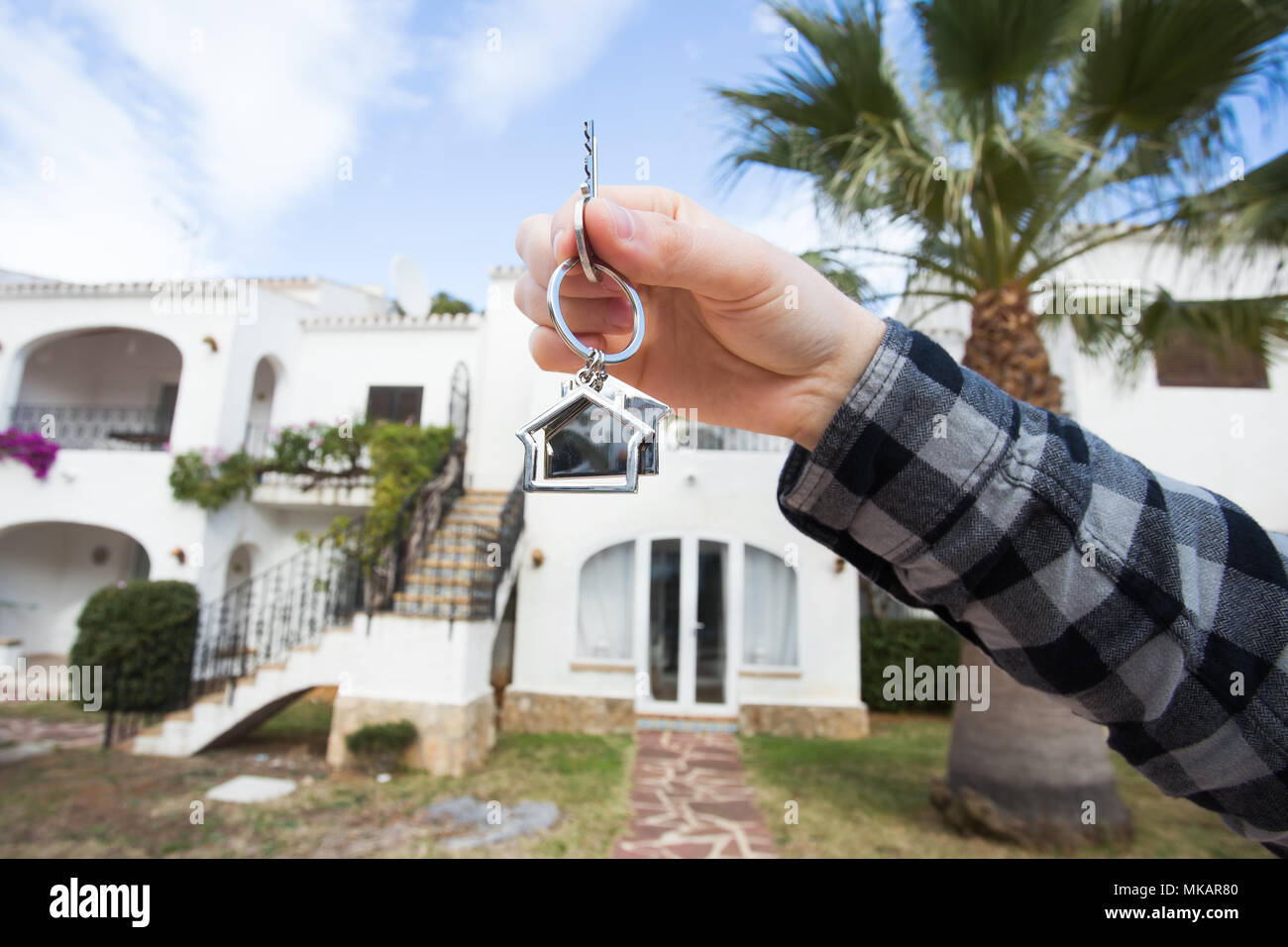 Holding house keys on house shaped keychain in front of a new home ...
