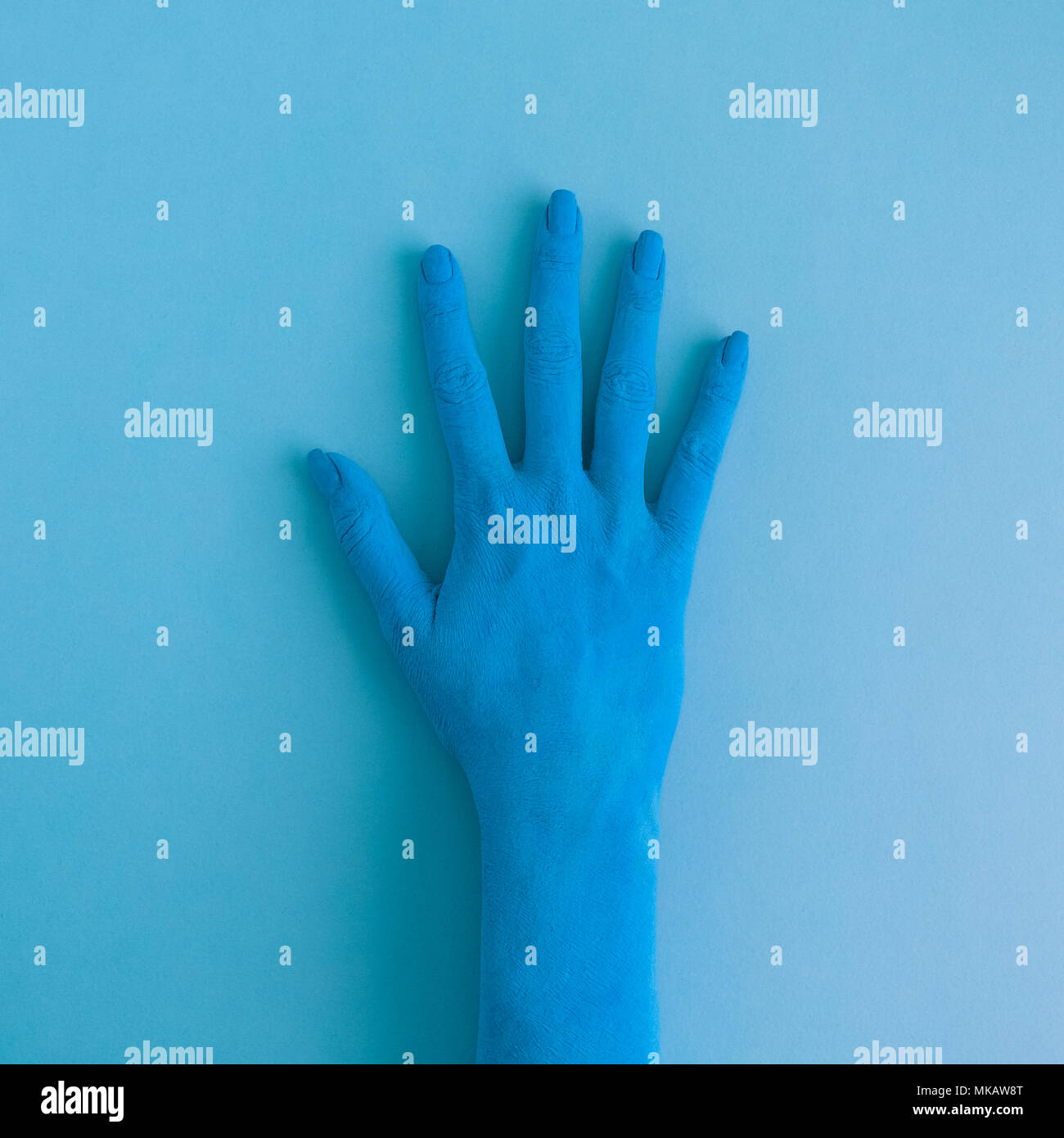 Close up of female hand colored in blue paint minimal creative concept ...