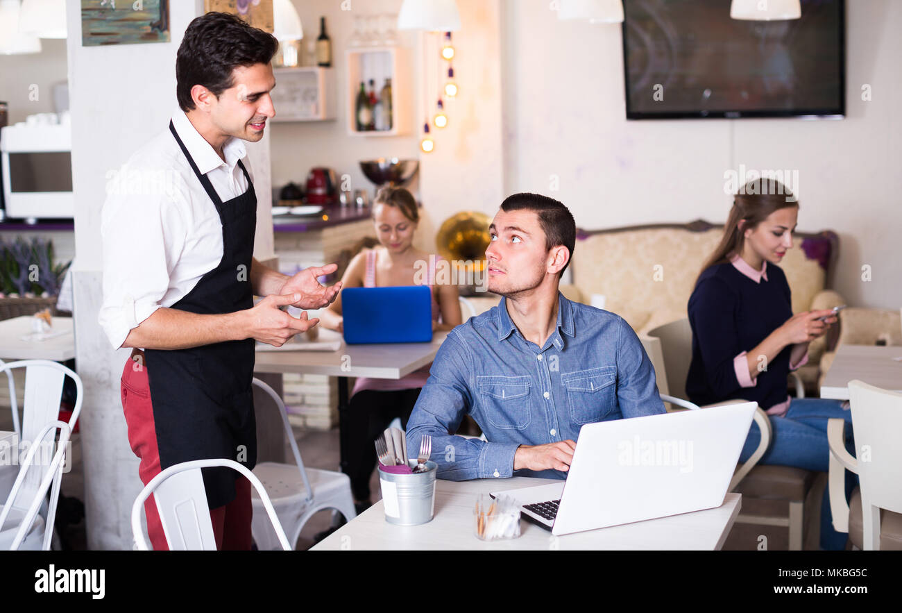 Waiter man is greeting visitors in cafe and taking order Stock Photo ...