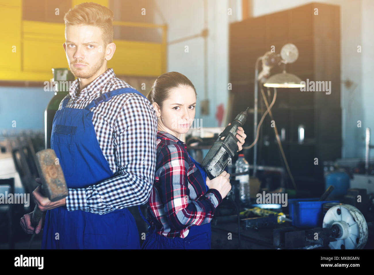 Portrait of two young positive masters are standing with tools in ...