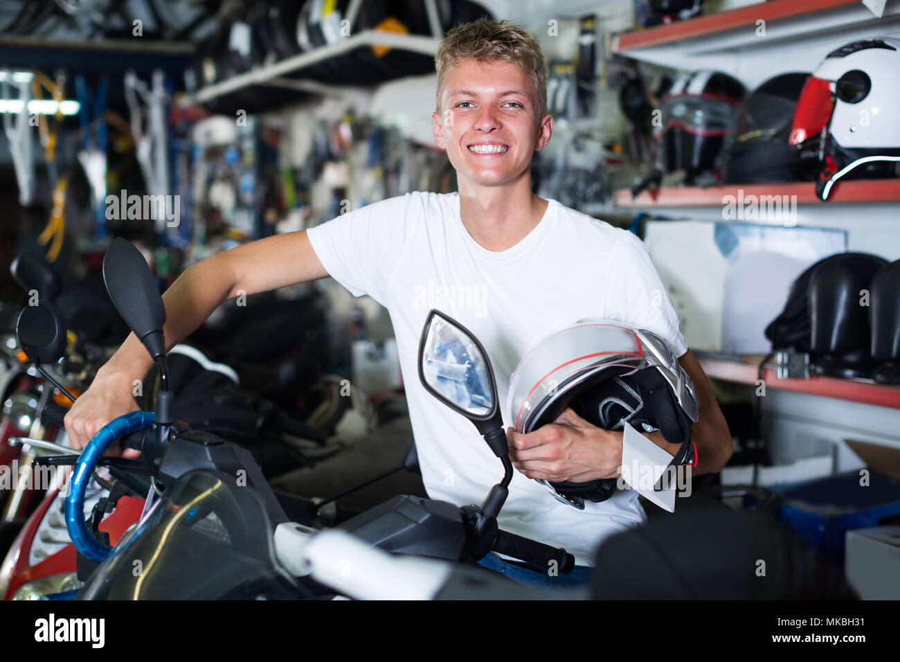 Customer man is sitting on the motorbike with helmet in store Stock ...