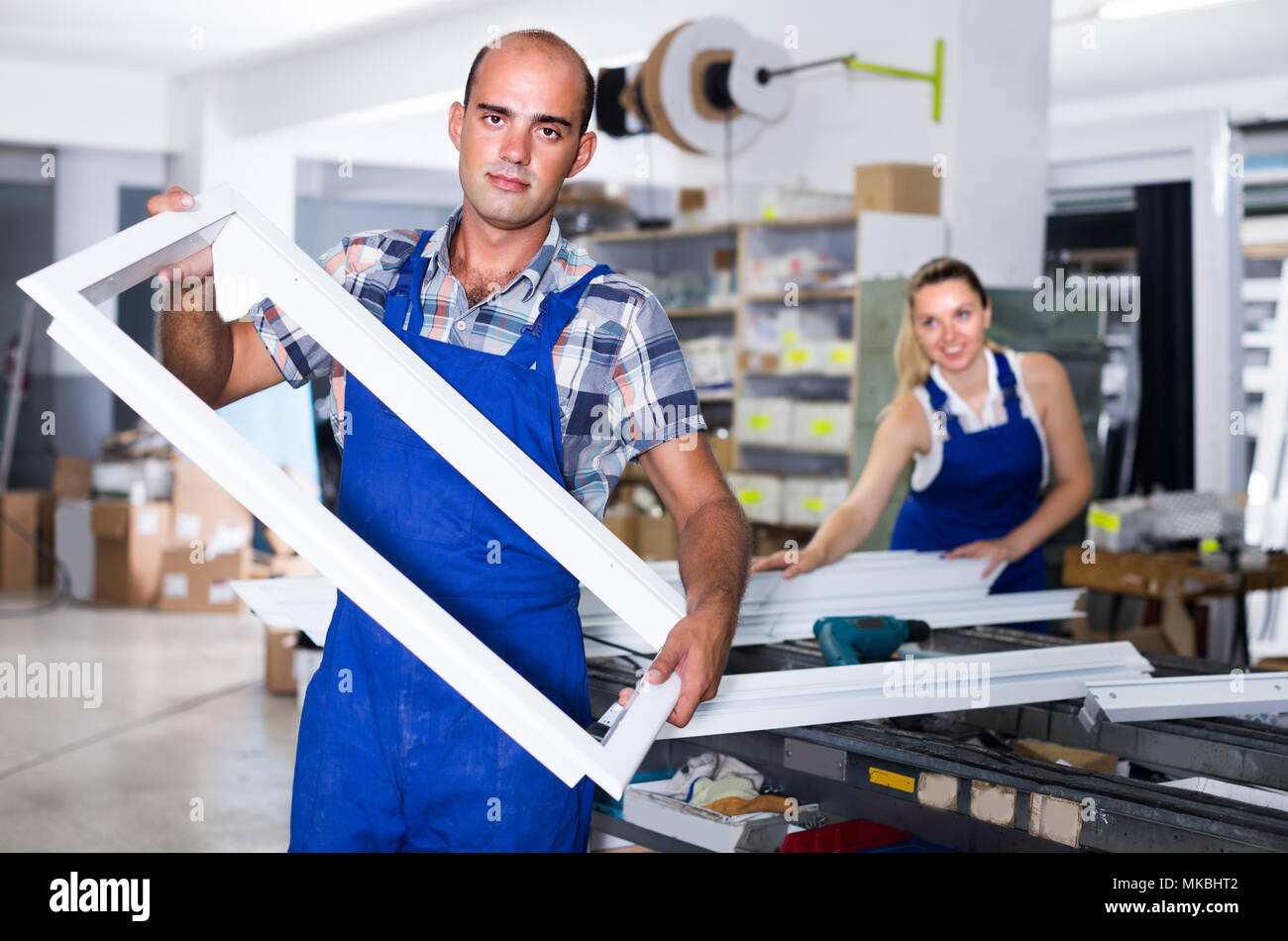 Worker in workwear is standing with window frame from pvc profile in ...