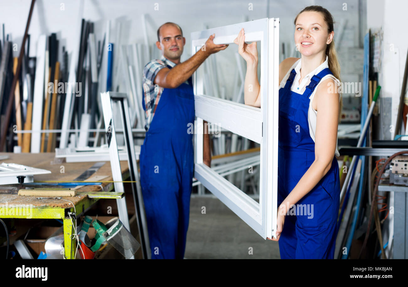 Happy brigade of two people working at workshop for production of pvc ...