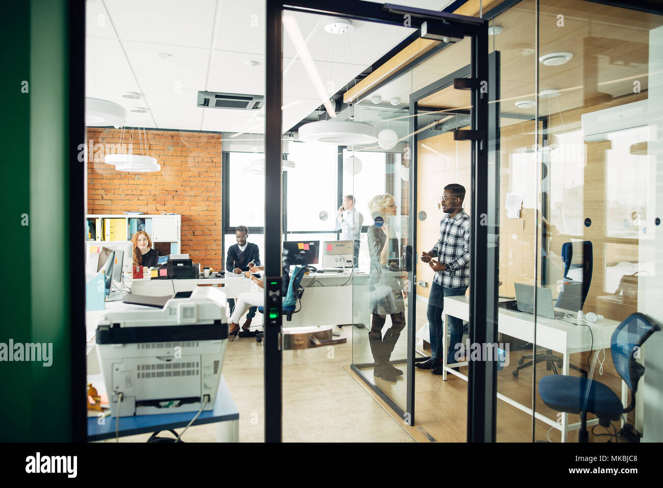 shot of busy office room with glass walls. hardworking business people ...