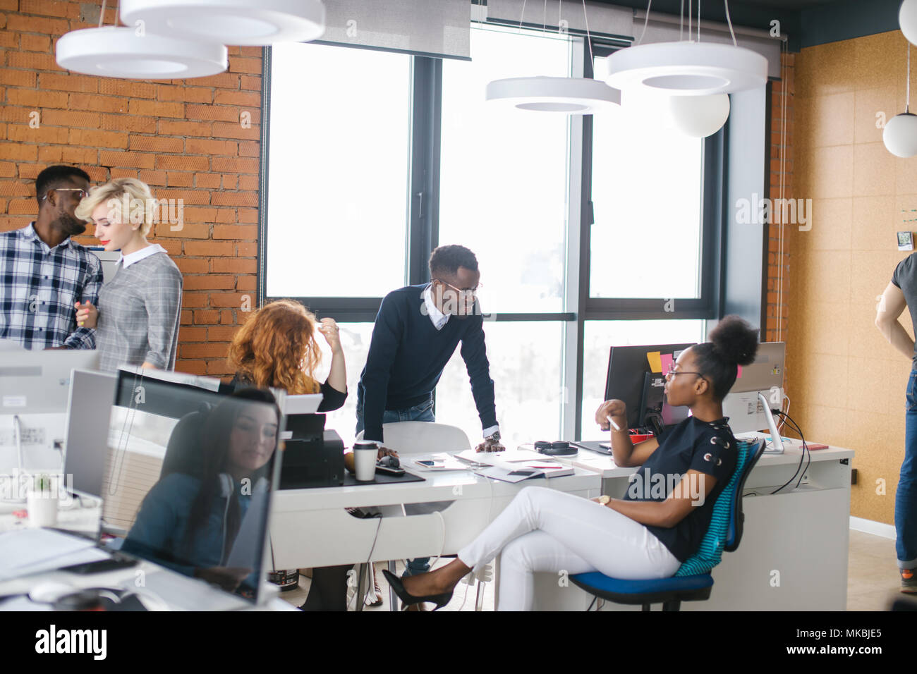 African leader of business team in glasses is leaning on the desk and ...