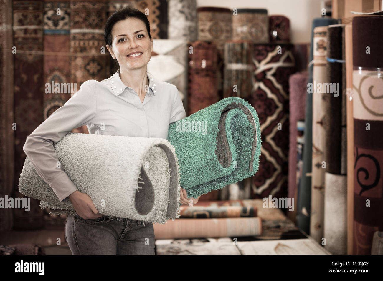 Female touching and choosing carpets in the store before the buying ...