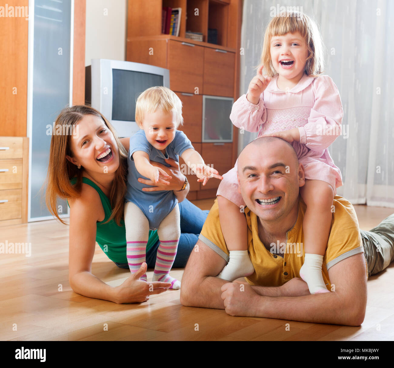 Joyful family with two kids enjoying time at home in the room Stock ...
