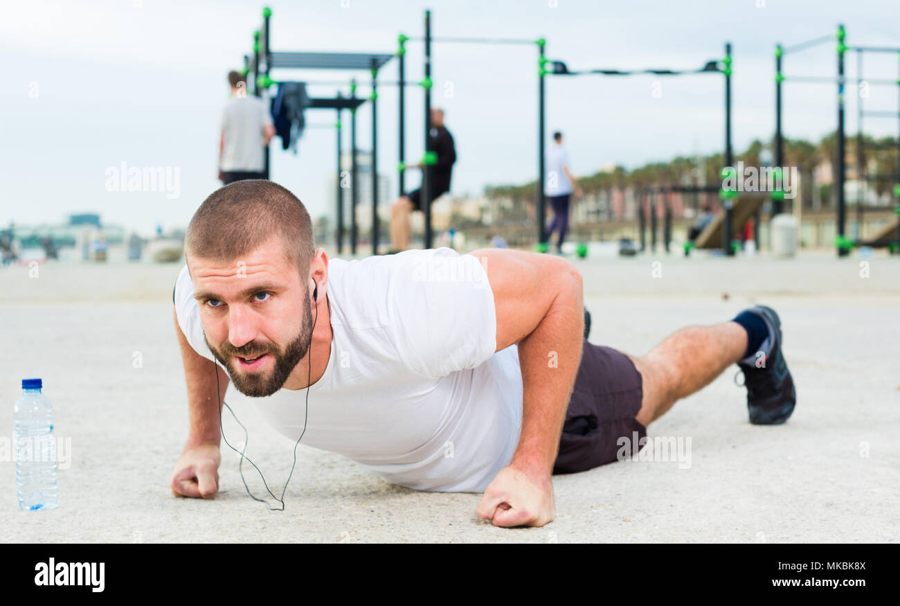 Strong man performs push-ups on an outdoor sports field Stock Photo - Alamy