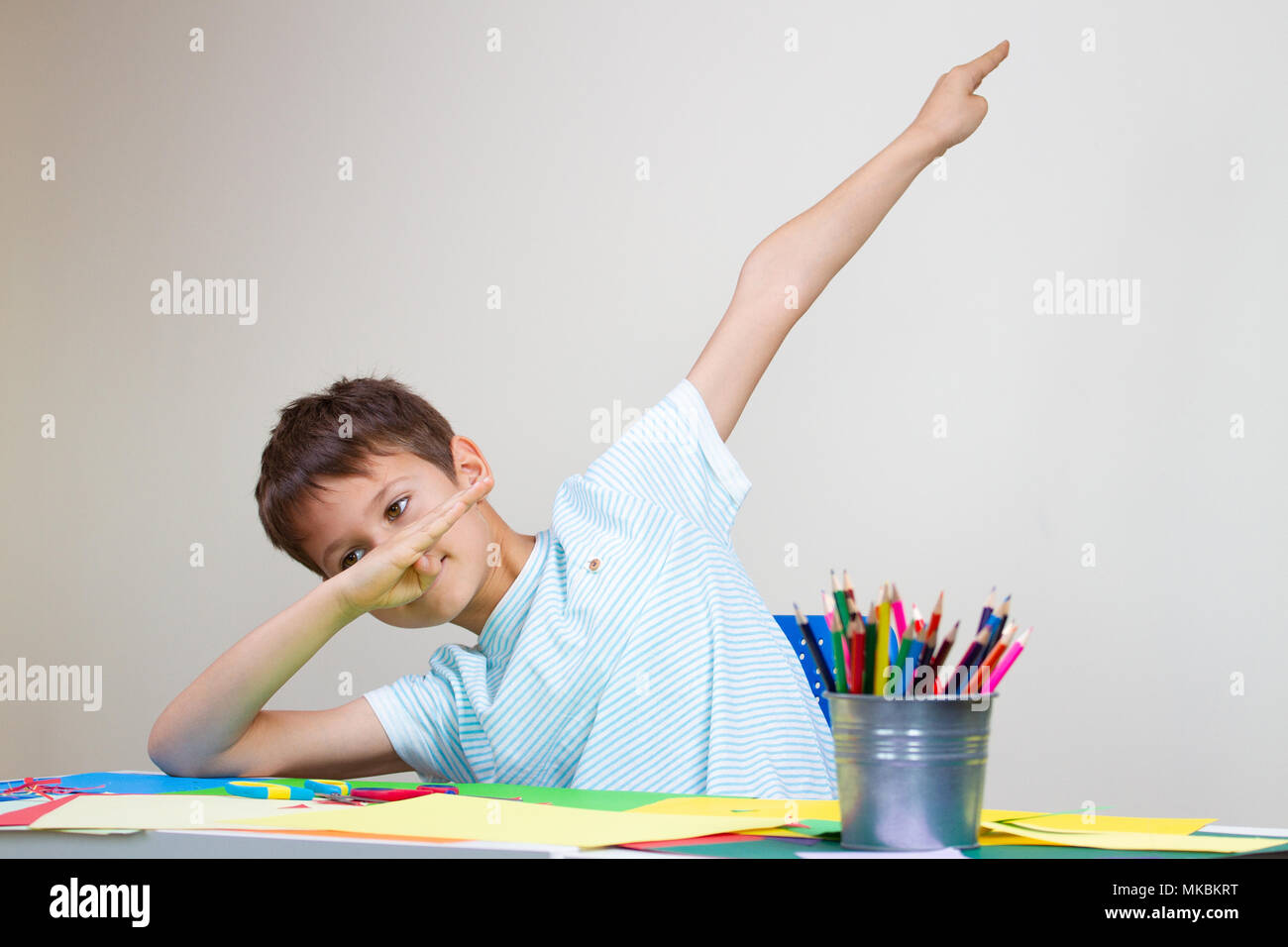 Boy sitting at the table and shows dab gesture Stock Photo - Alamy