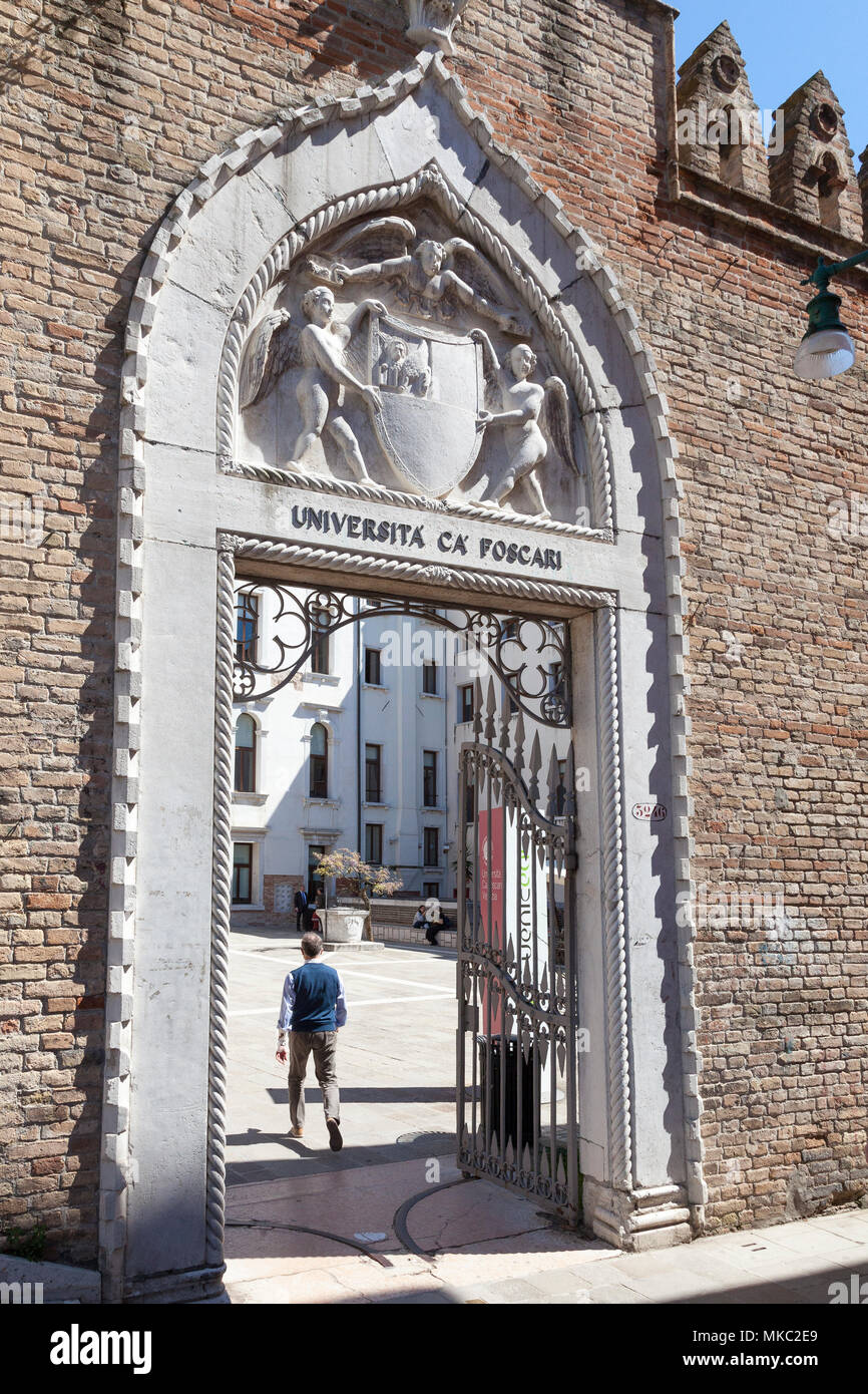 Man entering the historic arched gate of Ca' Foscari University, Venice ...