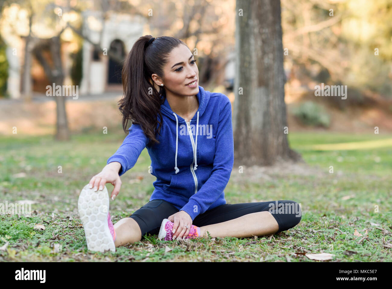 Happy young woman stretching before running outdoors. Runner girl in an ...