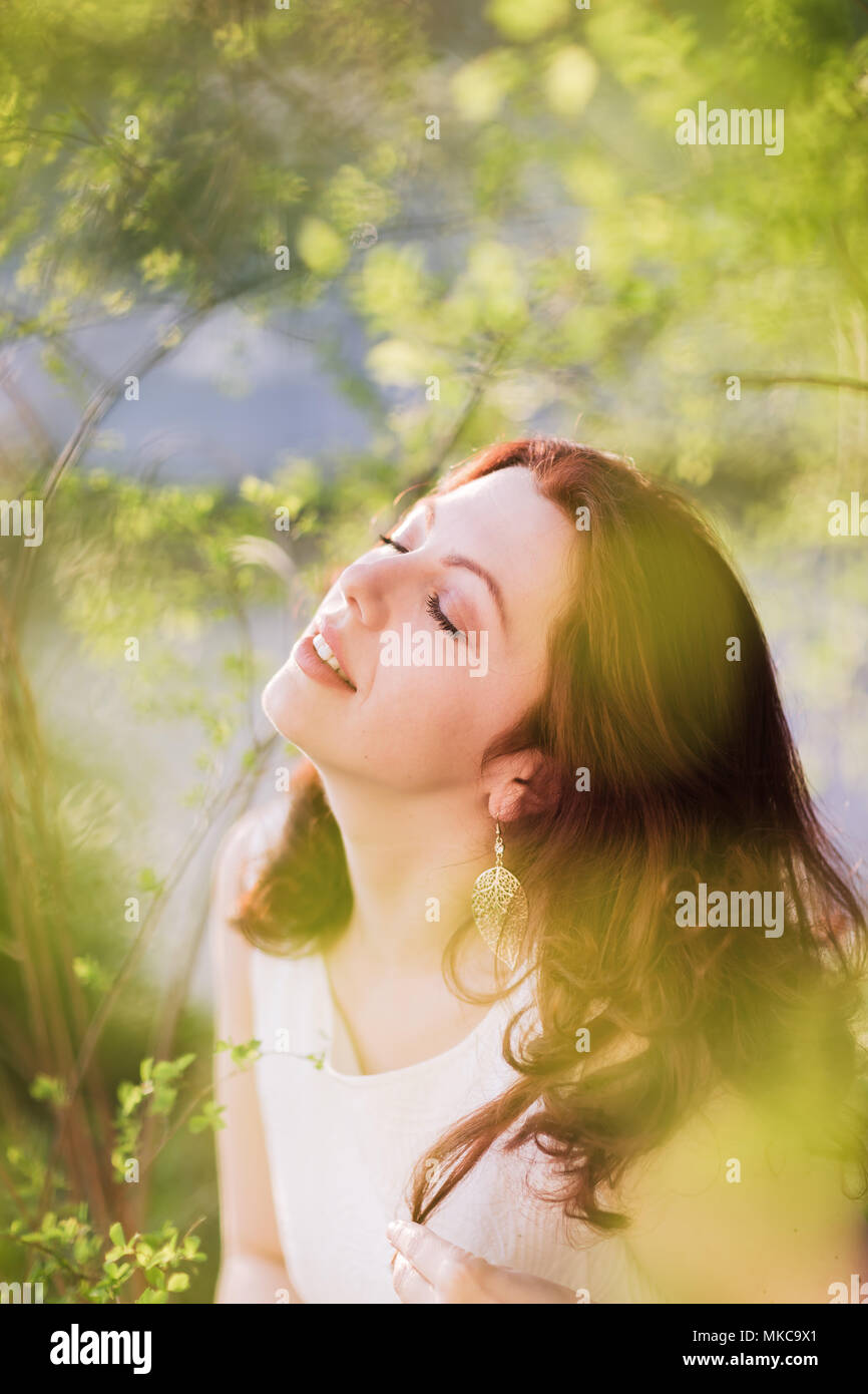 headshot of a woman who poses in a spring bush Stock Photo - Alamy