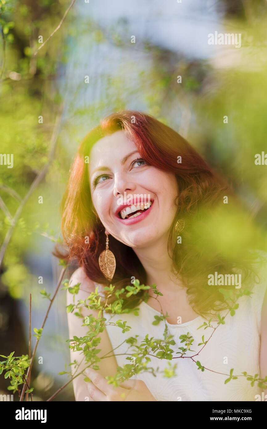 headshot of a woman who poses in a spring bush Stock Photo - Alamy