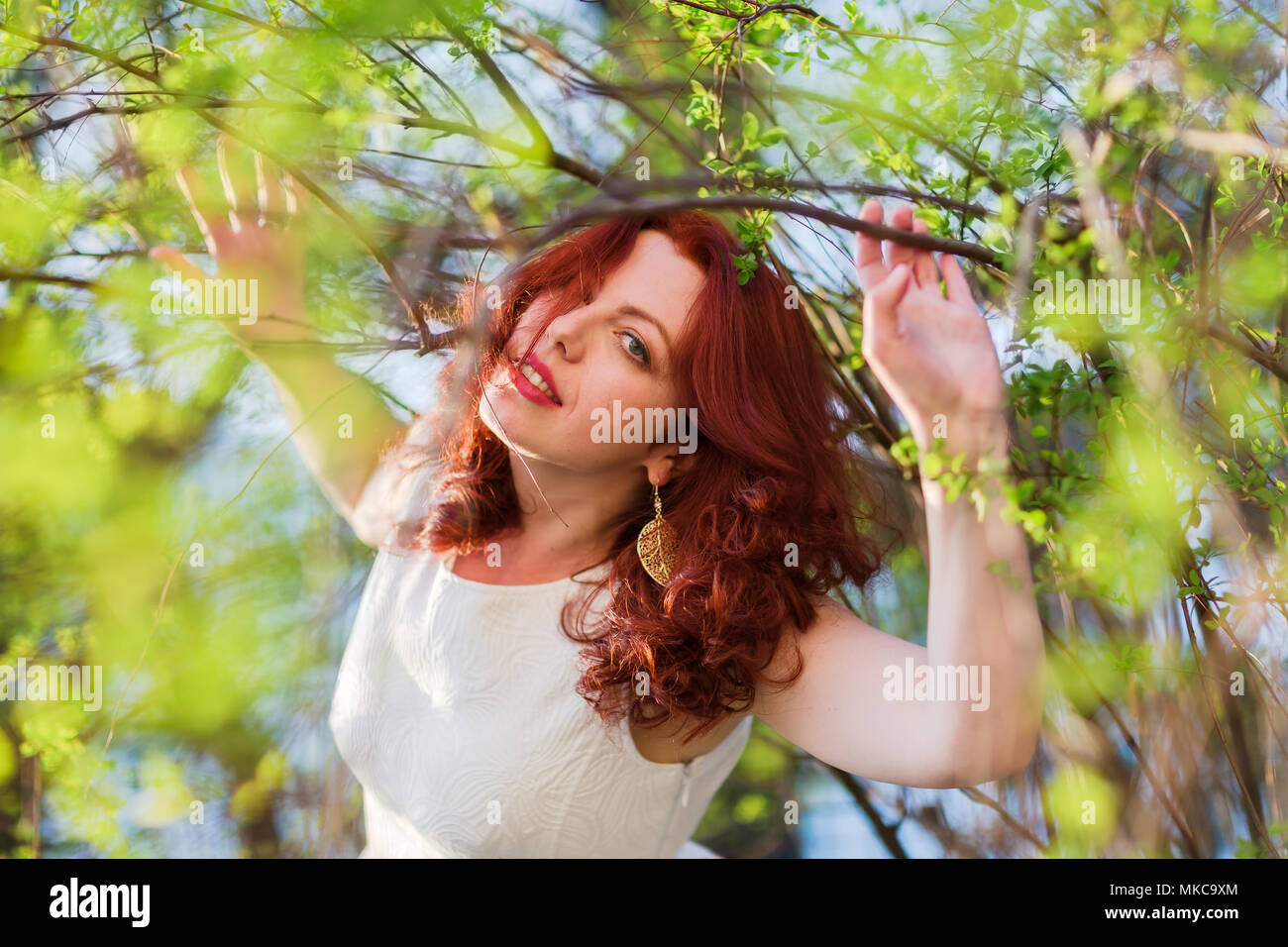 headshot of a woman who poses in a spring bush Stock Photo - Alamy