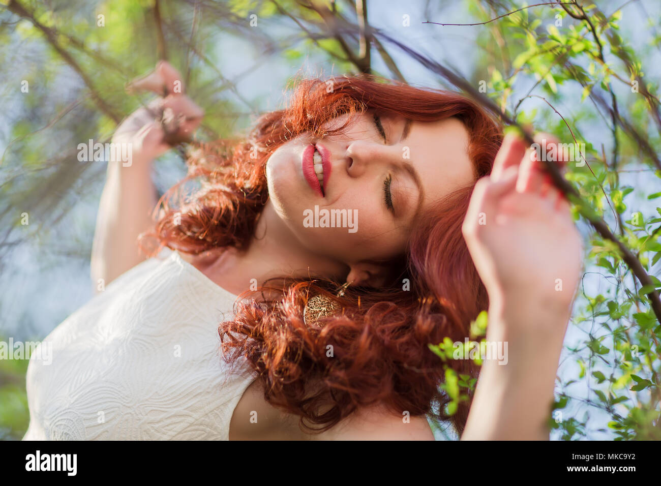 headshot of a woman who poses in a spring bush Stock Photo - Alamy