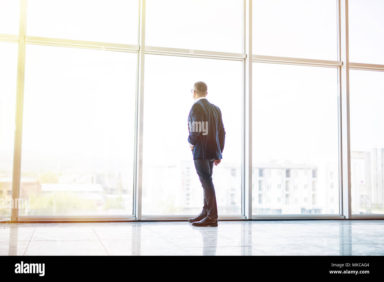 Senior businessman looking out a window in office Stock Photo - Alamy