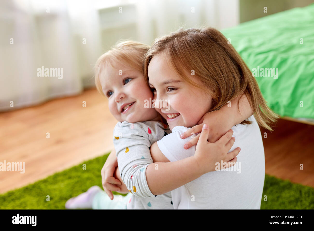 happy little girls or sisters hugging at home Stock Photo - Alamy