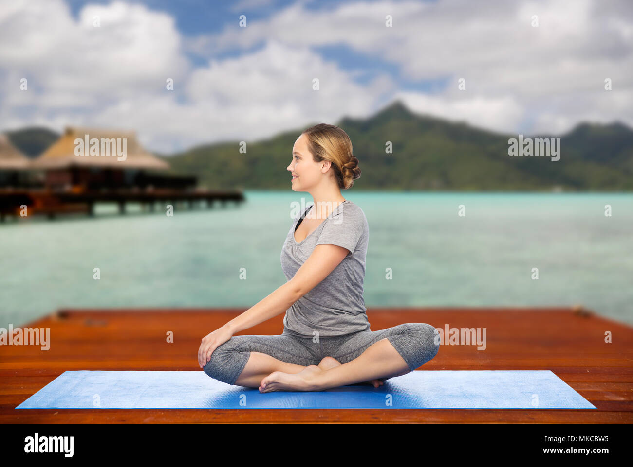 woman making yoga in twist pose on mat outdoors Stock Photo - Alamy
