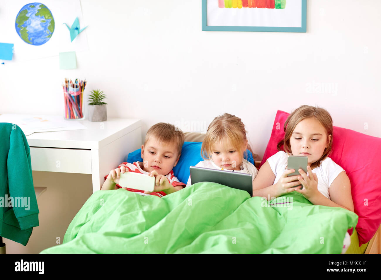 kids with tablet pc and smartphones in bed at home Stock Photo - Alamy