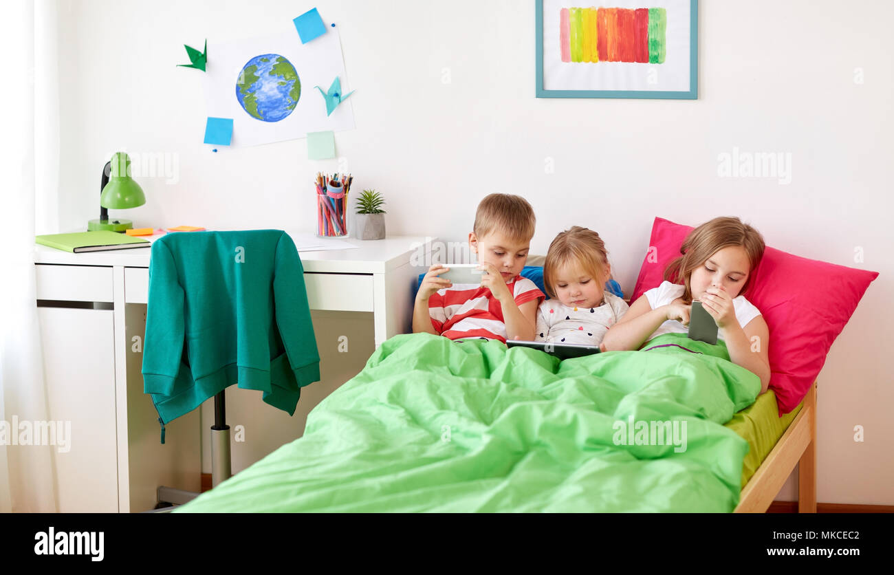 kids with tablet pc and smartphones in bed at home Stock Photo - Alamy