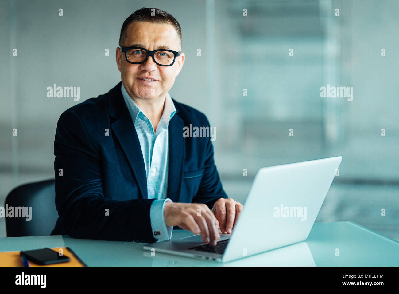 Positive Business Leader Sitting at Office Desk Stock Photo - Alamy
