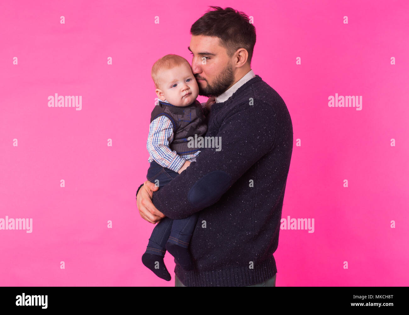 Portrait of happy father with a baby son isolated on a pink background ...