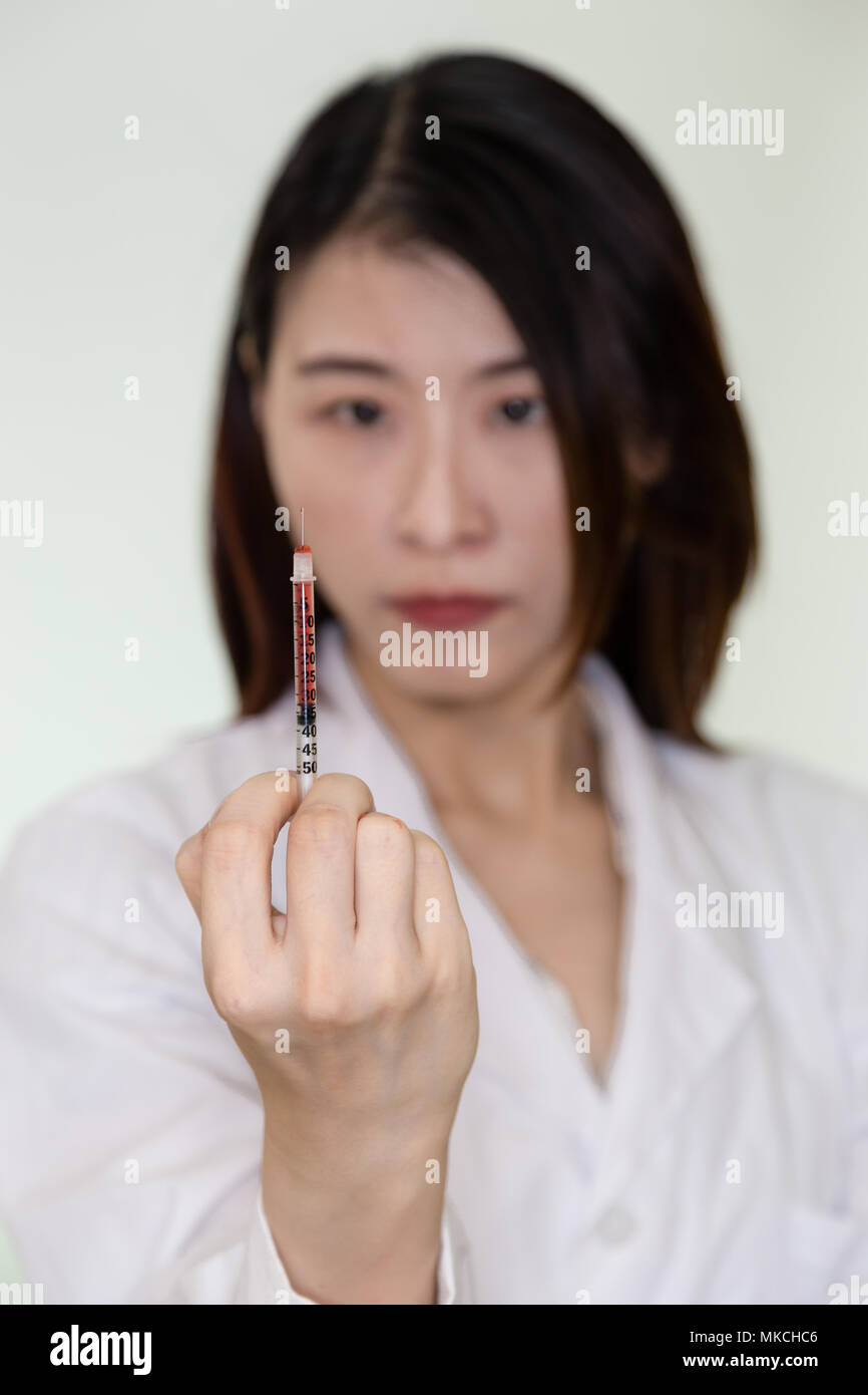 Scary Asian nurse holding a syringe in hand, filter Stock Photo - Alamy