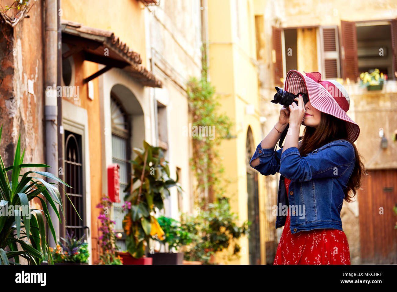 Side view of pretty woman in hat aiming with camera at Trastevere in ...