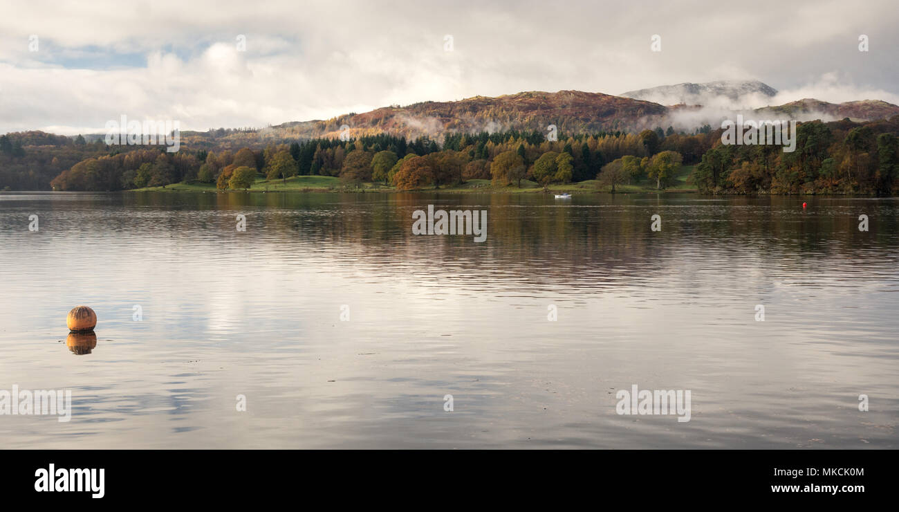 Mist rises from woodland in autumn colour at Ambleside on Windermere ...