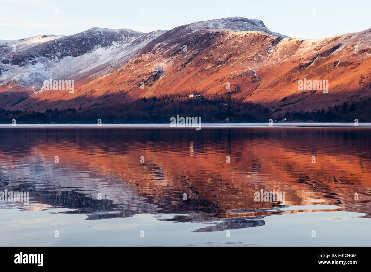 Winter snow lies on Catbells mountain, reflected in Derwent Water lake ...