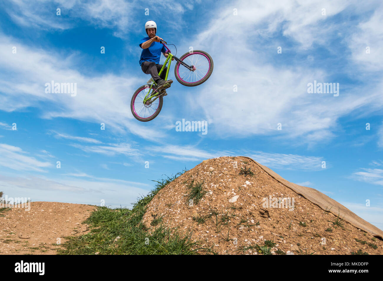 Side view of sportsman on mountain bike flying over hill in the nature ...