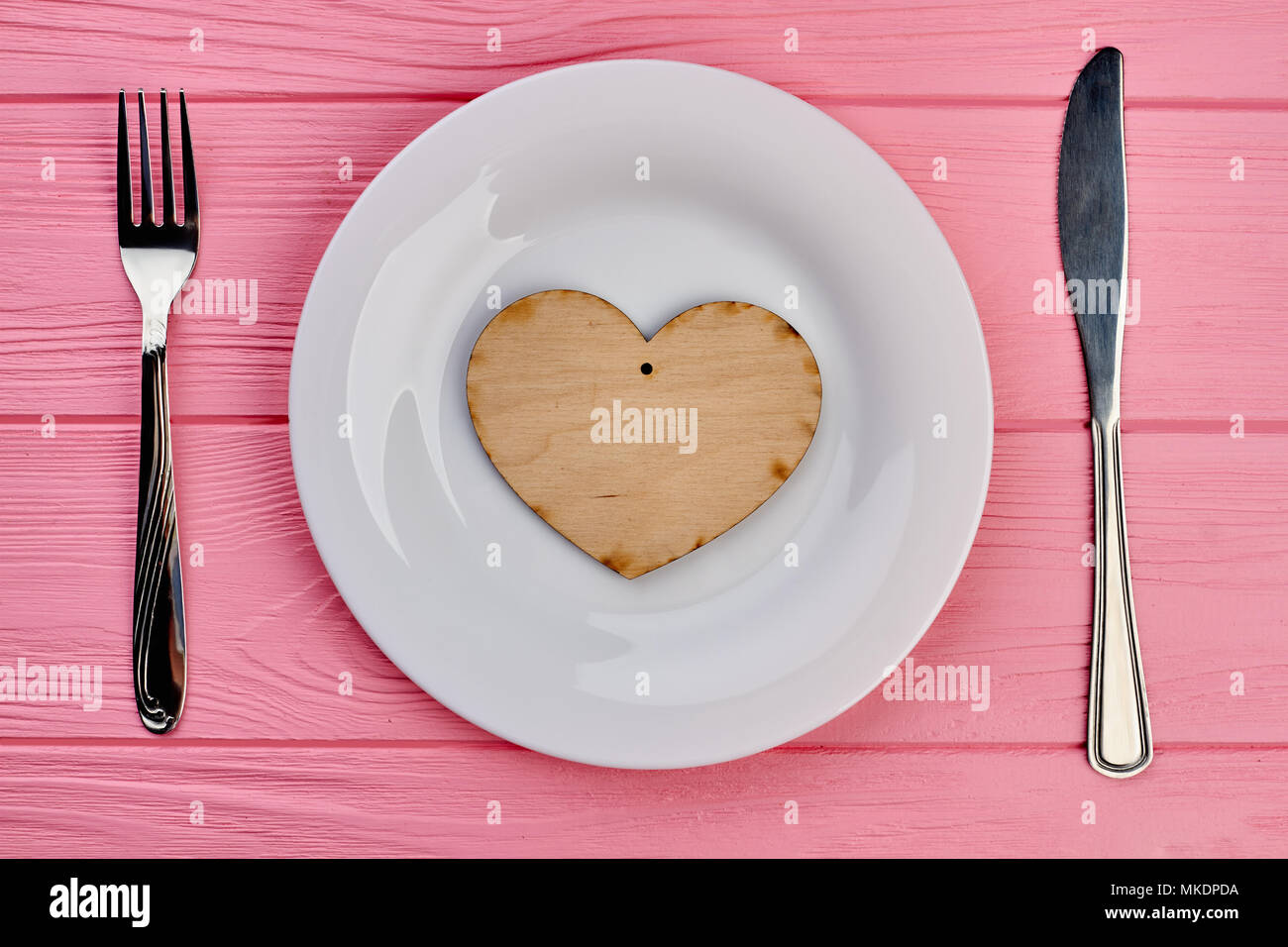 Plywood heart on white plate. Table setting for Valentines Day with ...