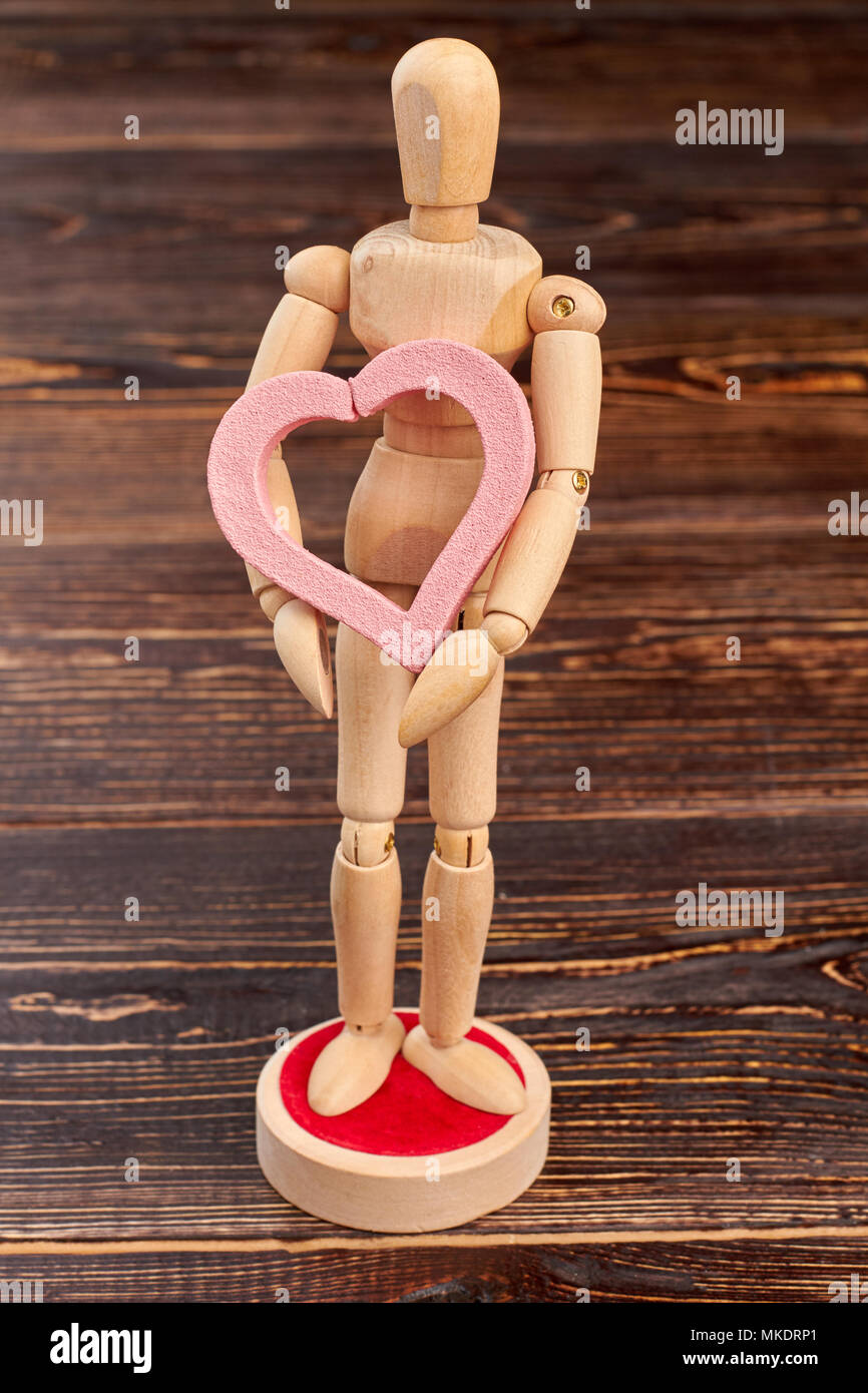 Wooden puppet holding pink heart. Wooden person holding beautiful ...