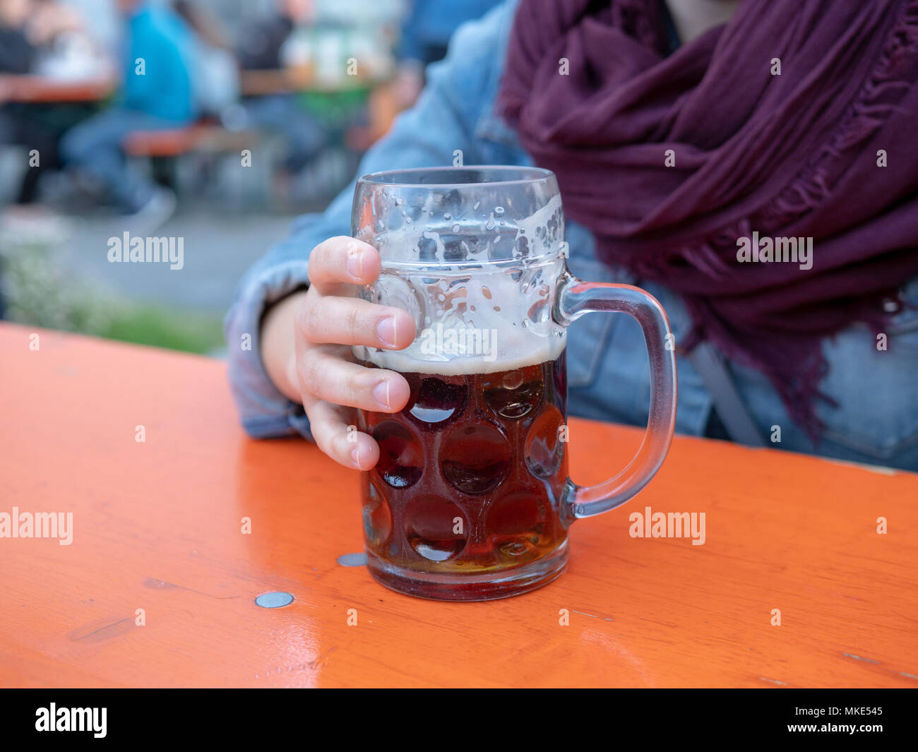 Woman gripping half empty beer mug mid drink Stock Photo - Alamy
