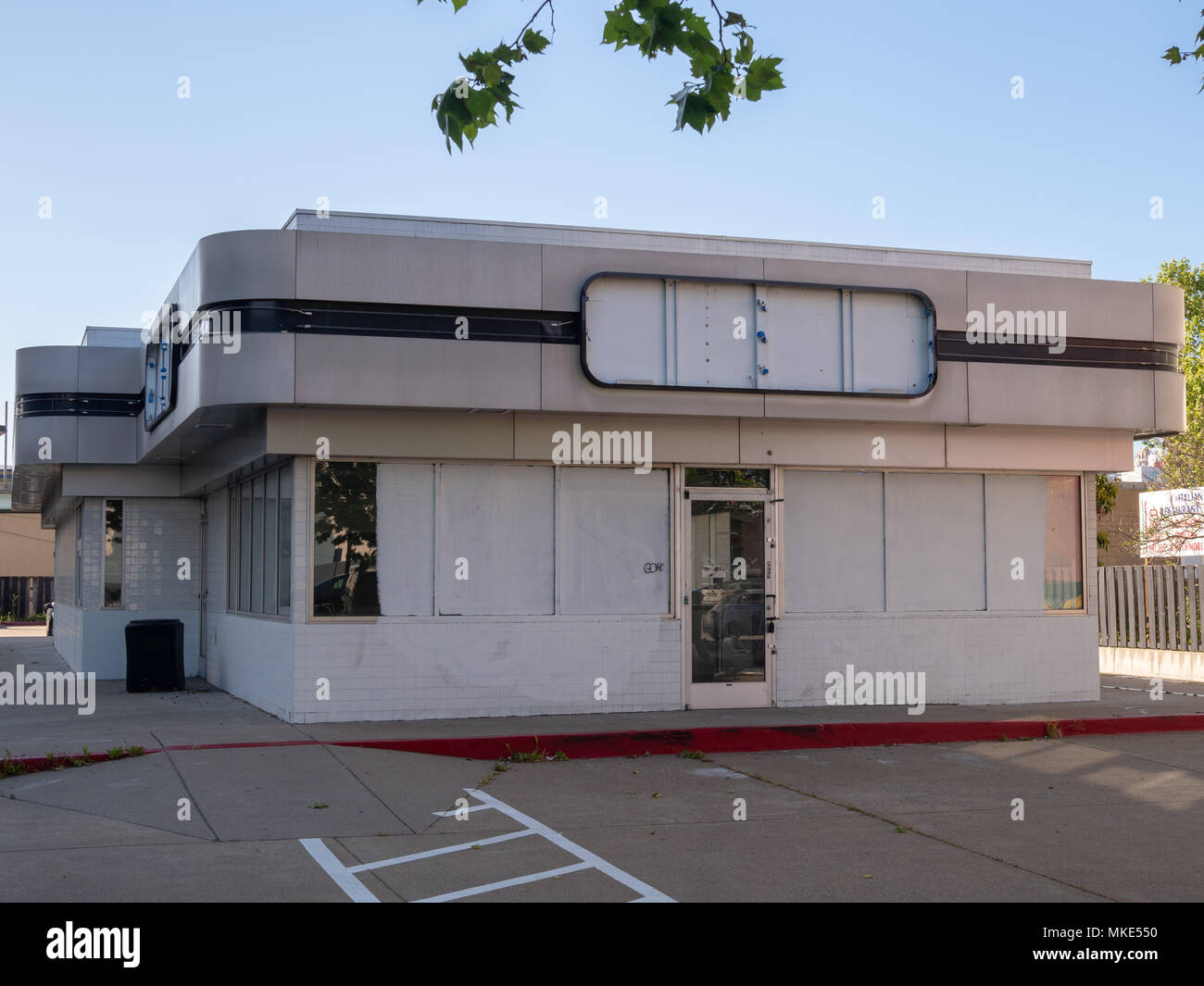 Abandoned, boarded up storefront in a parking lot in an urban city area ...
