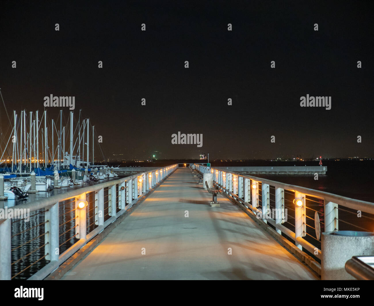 A dark, lit concrete pier in the night time with no pedestrians Stock ...