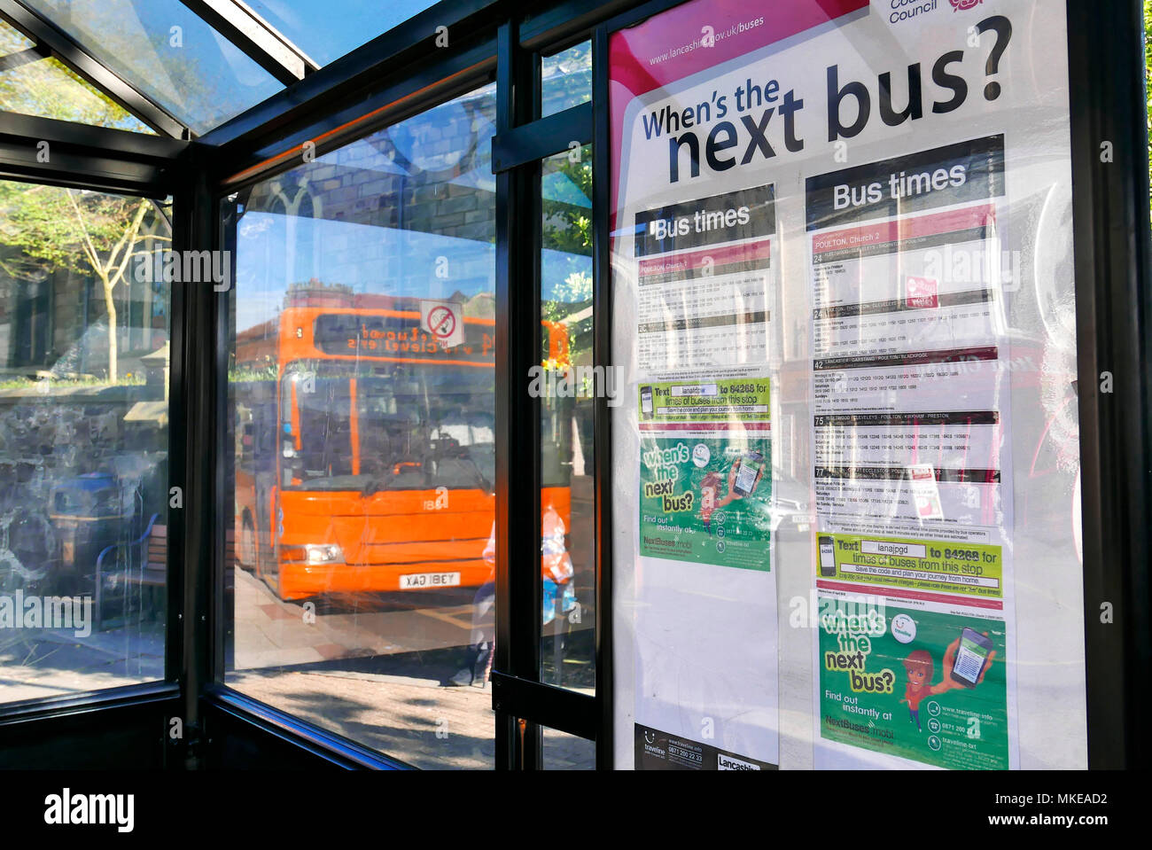 Bus timetables posted on window of bus shelter with reflection of bus ...