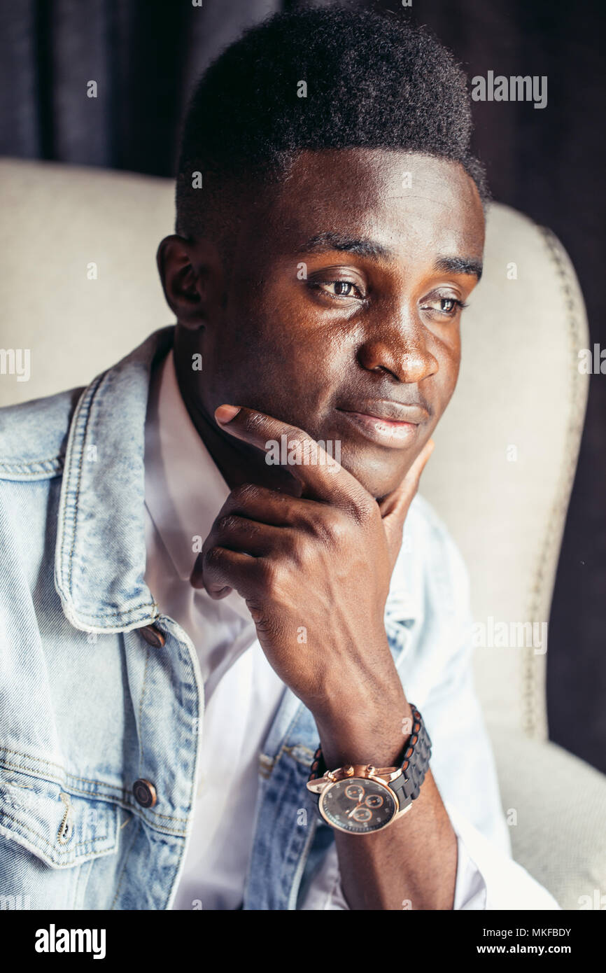 close up portrait of african young man sitting in cafe and thoughtfully ...