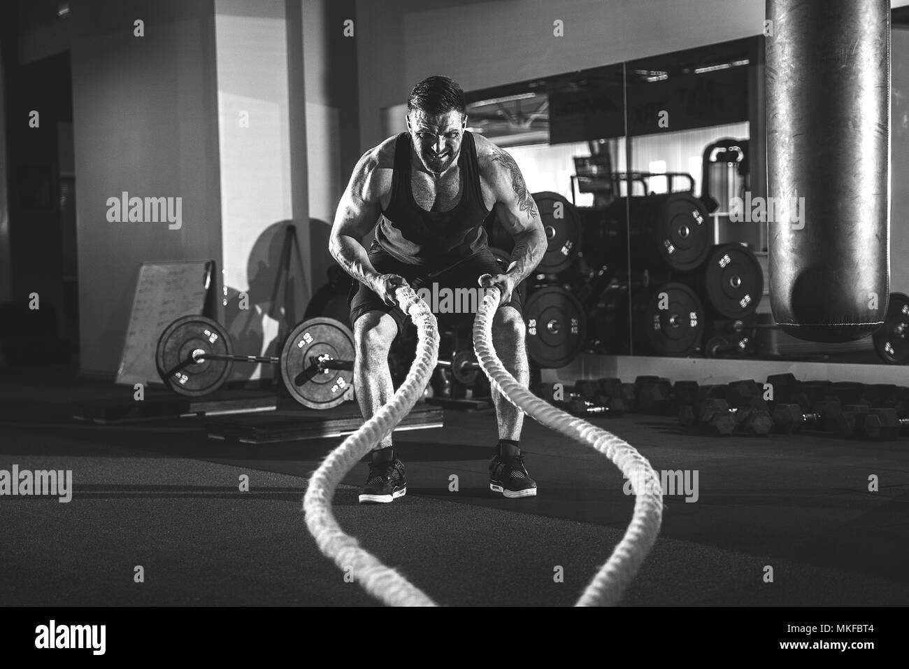 Muscular powerful aggressive man training with rope in functional ...