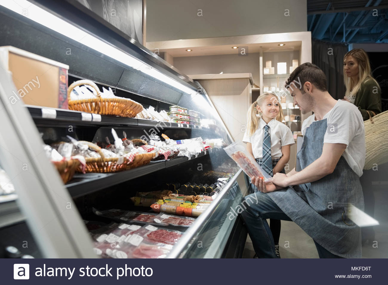Worker helping mother and daughter grocery shopping in market Stock ...
