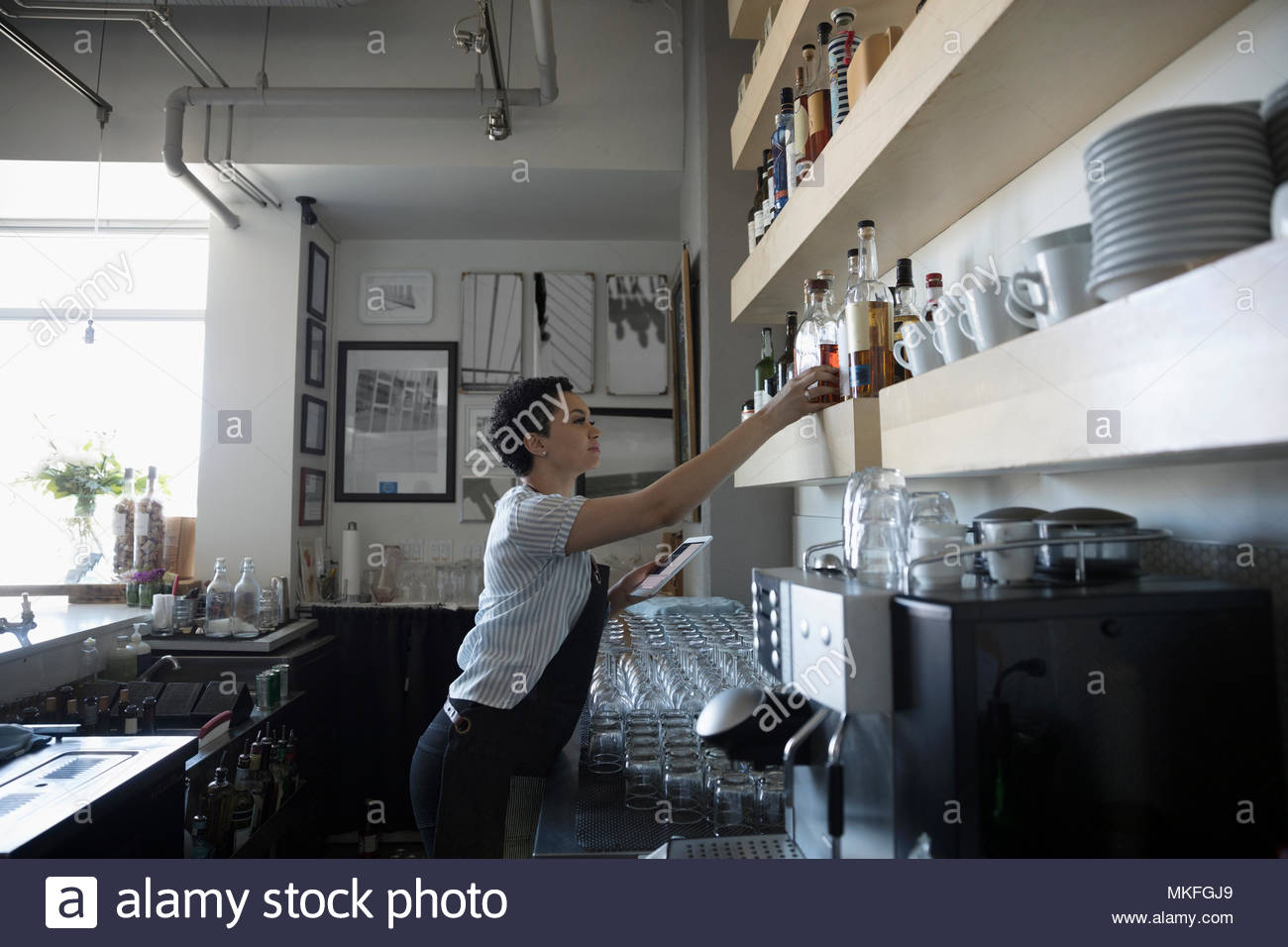 Female bartender organizing alcohol bottles in bar Stock Photo - Alamy